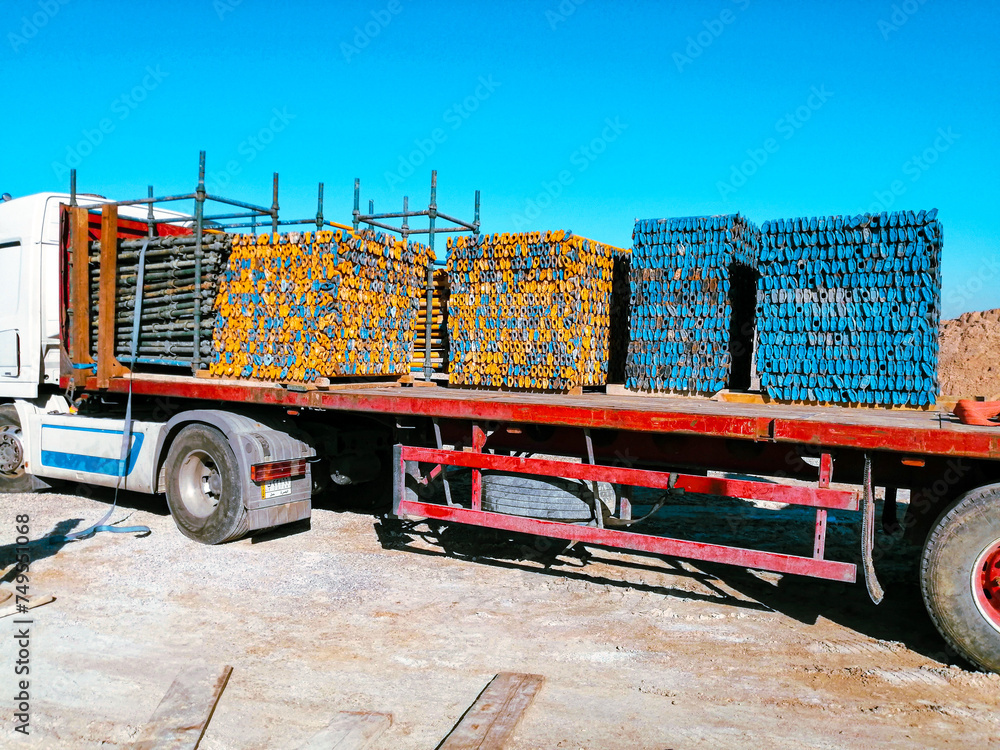 A truck is carrying a load of construction materials. The truck is red ...