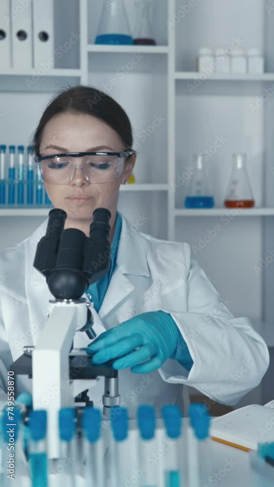 A medical microbiologist with a microscope conducts research on ...