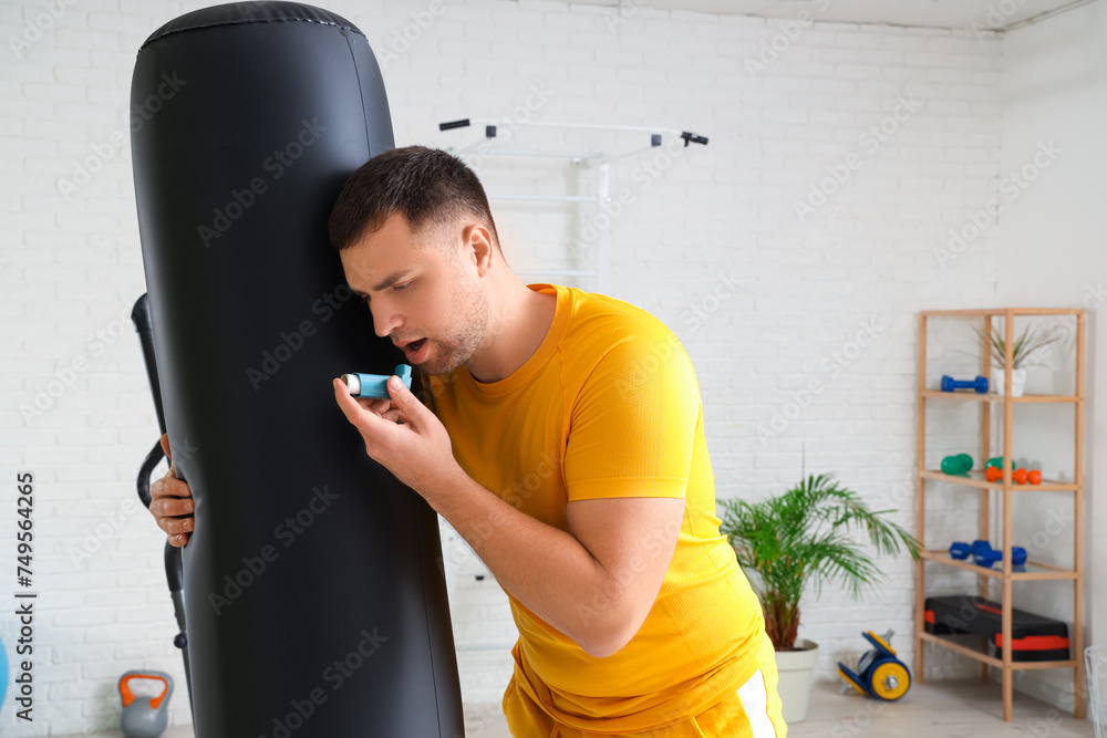 Sporty young man using inhaler near punching bag in gym Stock Photo ...