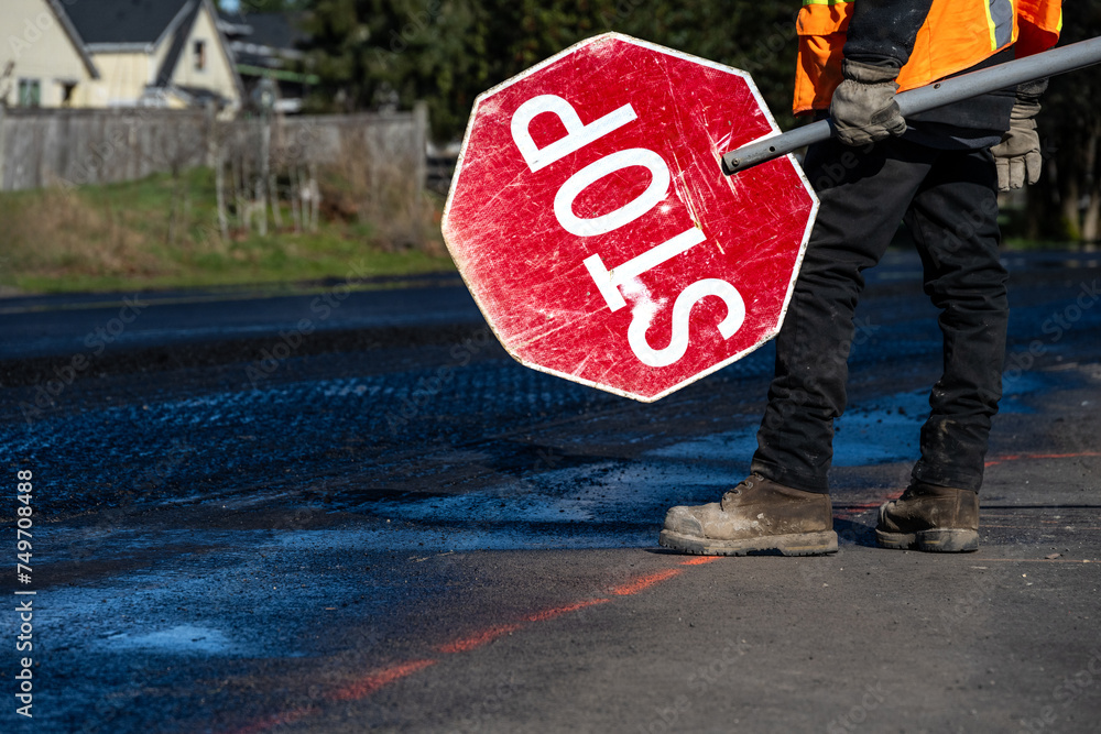 Traffic control worker in orange reflective safety vest with temporary ...