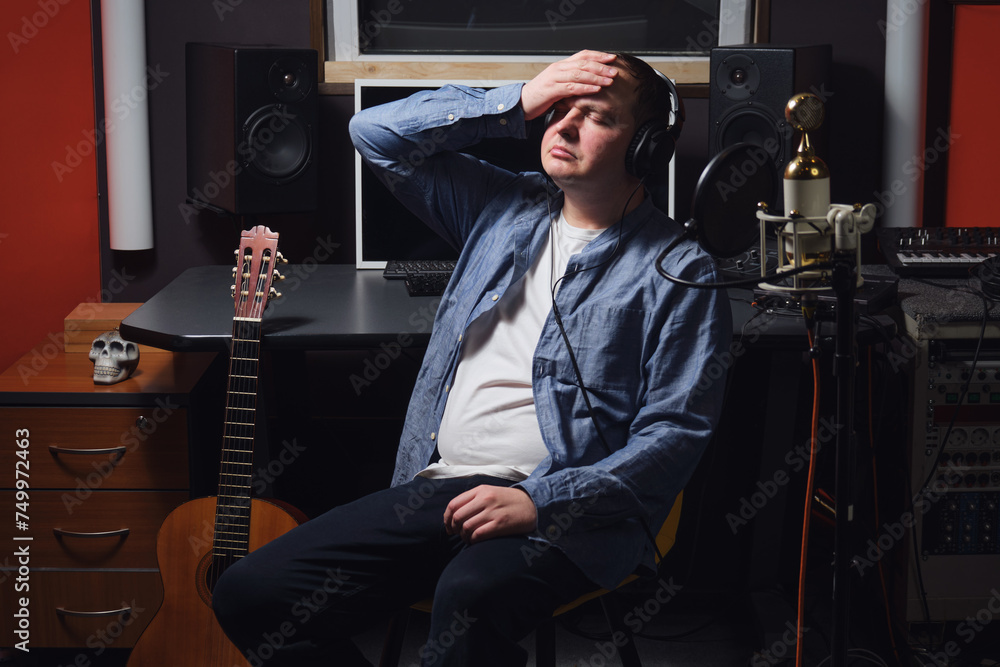 Sad musician holding his sore head in recording studio, losing his ...
