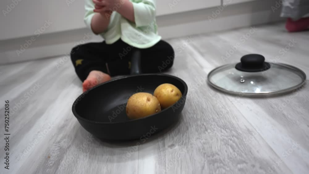 Vidéo Stock Toddler joyfully plays on the floor with a kitchen skillet ...