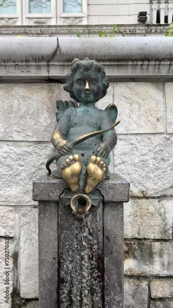 4K vertical video. Bronze statue of child angel with wings with rubbed ...
