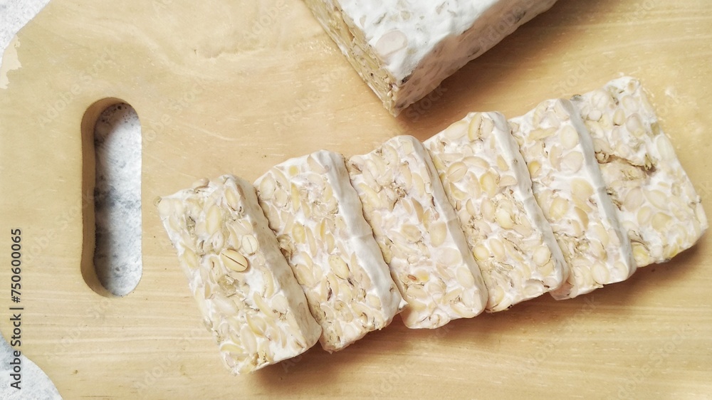 Raw tempe in slices on wooden chopping board. Raw Tempeh, traditional ...