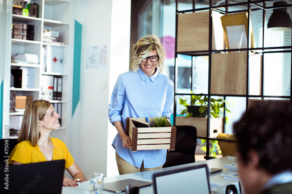 New young female employee bringing box with belongings to office desk ...