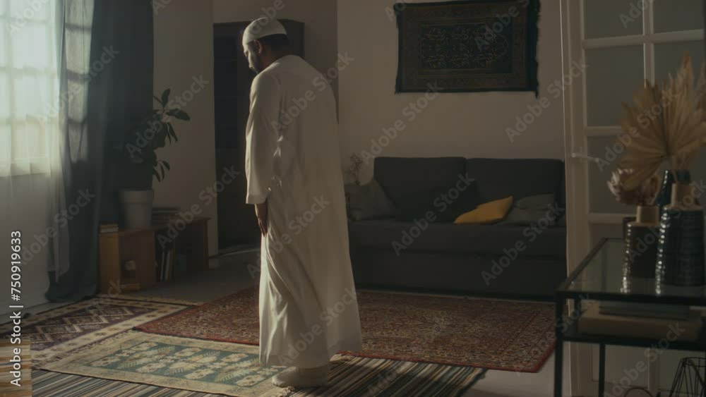 Rear wide footage of unidentified religious man in white cap and thawb ...