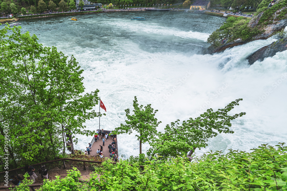 Tourists watch the massive waterfalls next to Laufen Castle at the ...