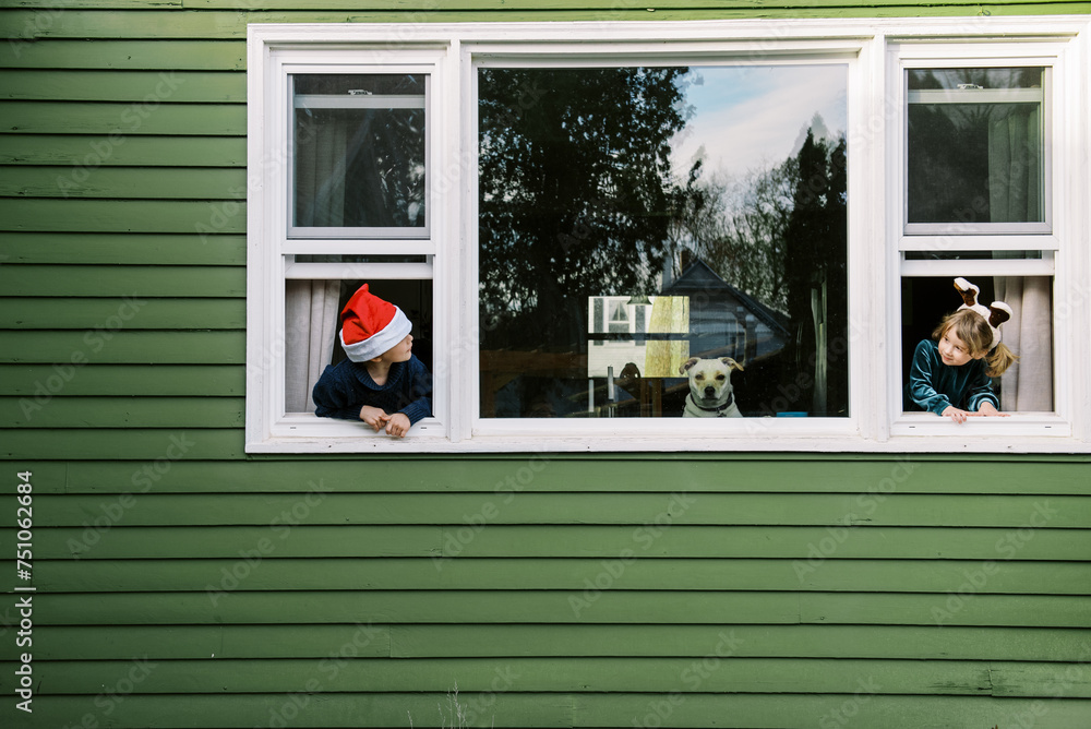 brother and sister in green house looking out of window with red hat ...
