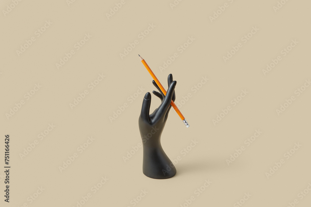 Black mannequin hand holding graphite pencil. Stock Photo | Adobe Stock