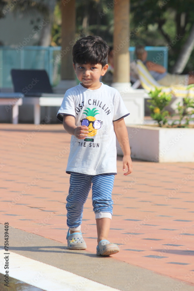 Cute and smart boy walking in the sun light at a beach side resort and ...