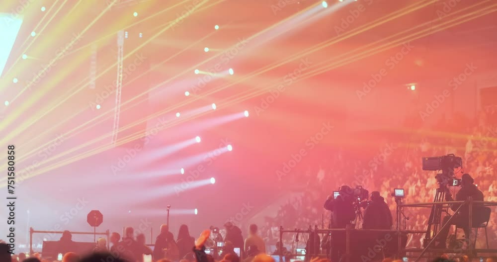 Professional cameraman filming concert scene in colorful spotlights ...