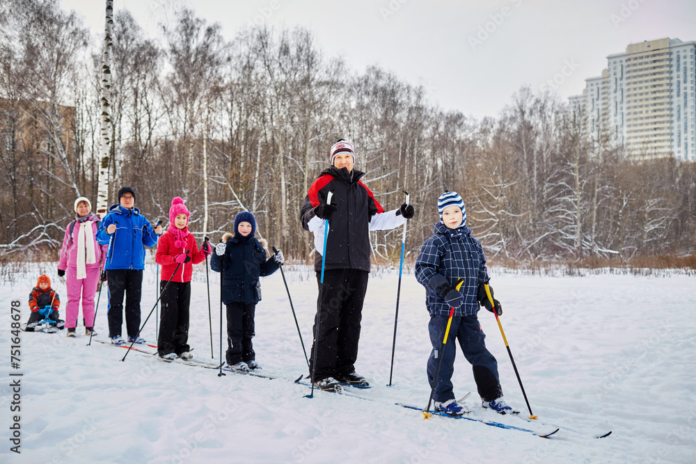 Group of seven people three adults and four children slide on skis and ...