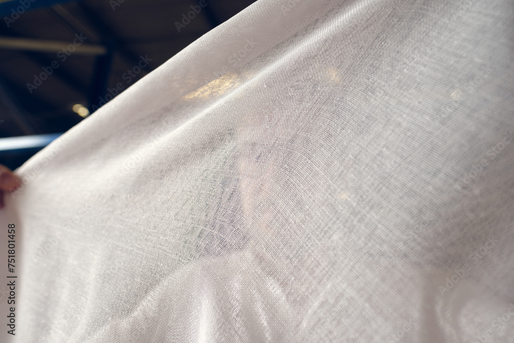 A hand holding up a thin see through white cotton sheet. Fabric ...