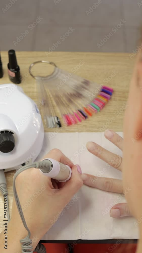The young woman carefully files off the old nail polish from her nails ...