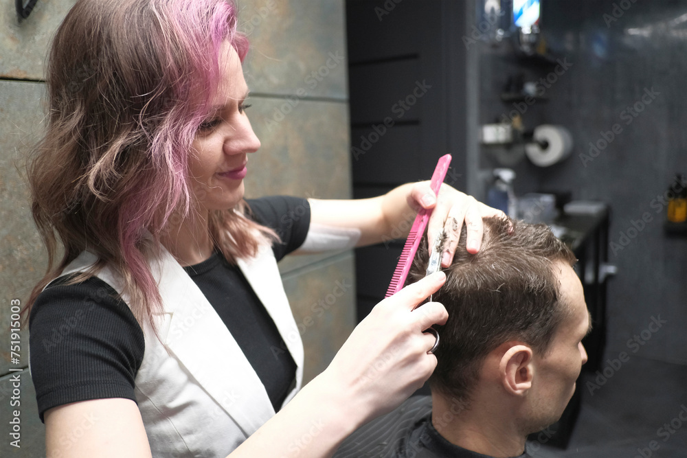 Barber using scissors while cutting hair of man sitting in modern ...