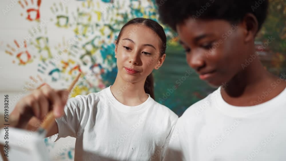 Diverse happy children paint canvas together with colorful stained wall ...