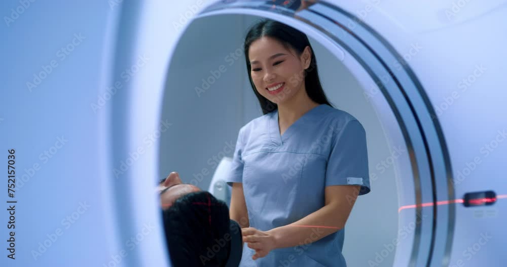 Asian doctor finishing magnetic resonance tomography. Patient going out ...