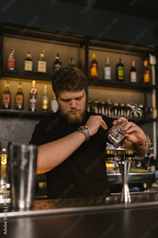 Skilled bartender rinses snifter before pouring cocktail. Adhering to ...
