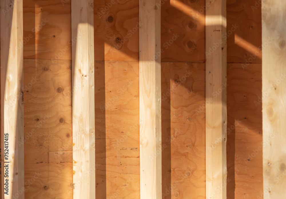 Detail from the inside of an interior wood stud wall showing the studs and plywood sheathing ...