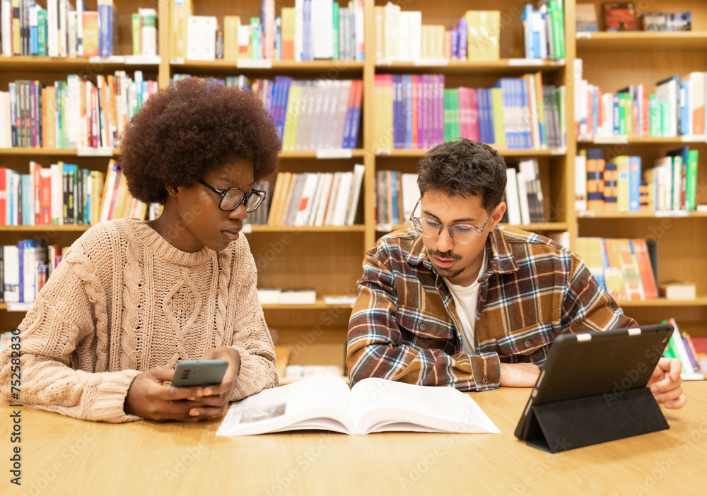 Students studying in library with books and digital devices Stock Photo ...