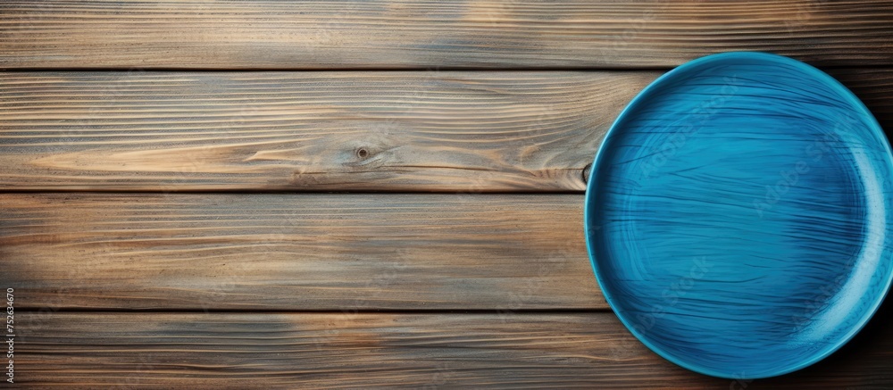A blue plate is placed on top of a simple wooden table, creating a ...