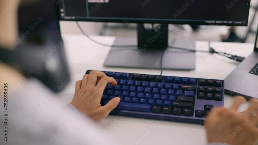A close-up view captures a programmer's hands as they swiftly navigate a mechanical keyboard ...