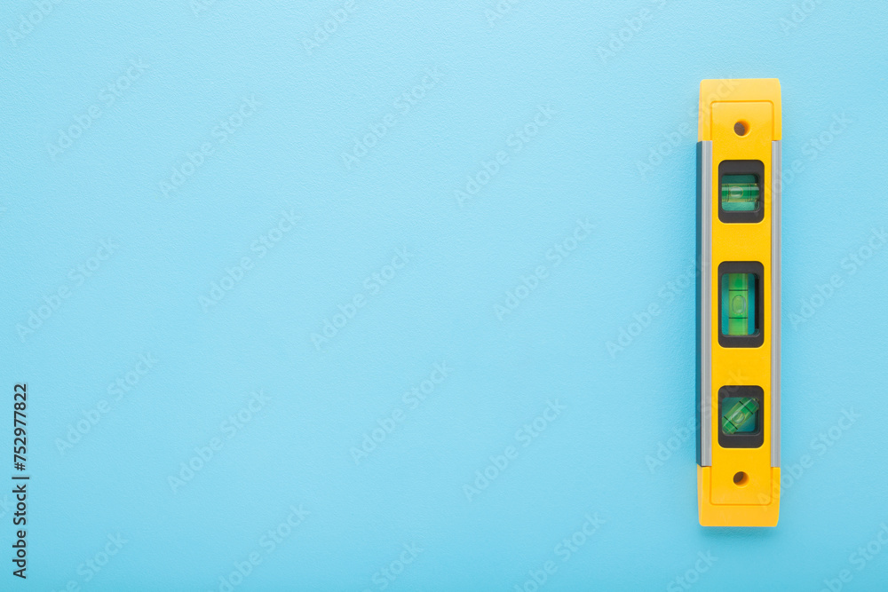 New yellow spirit level on light blue table background. Pastel color ...