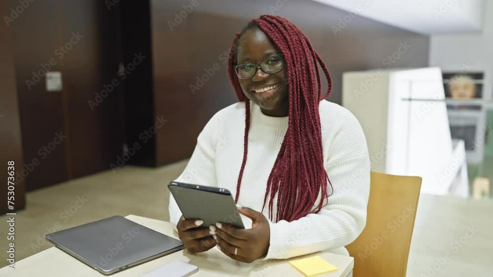 African woman with braids using tablet in modern office, portraying ...