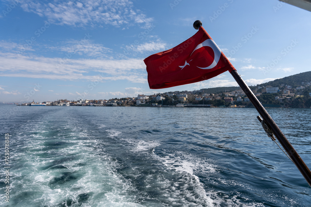 A red flag with a crescent moon on it is flying on a boat in the ocean ...