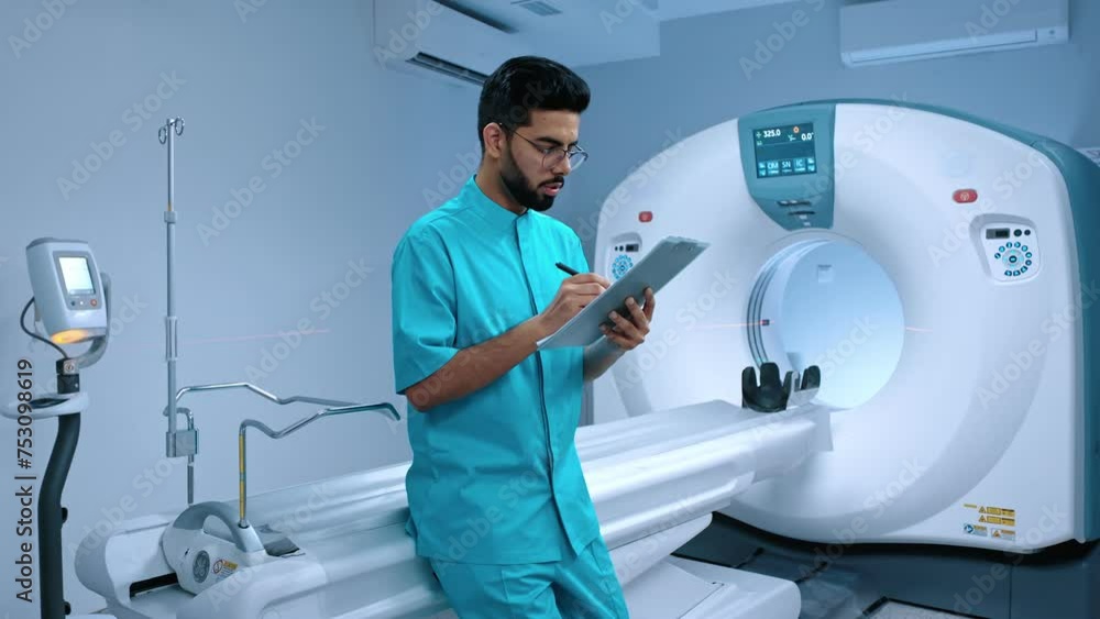 Indian tomographer making notes with pen. Serious doctor at background ...