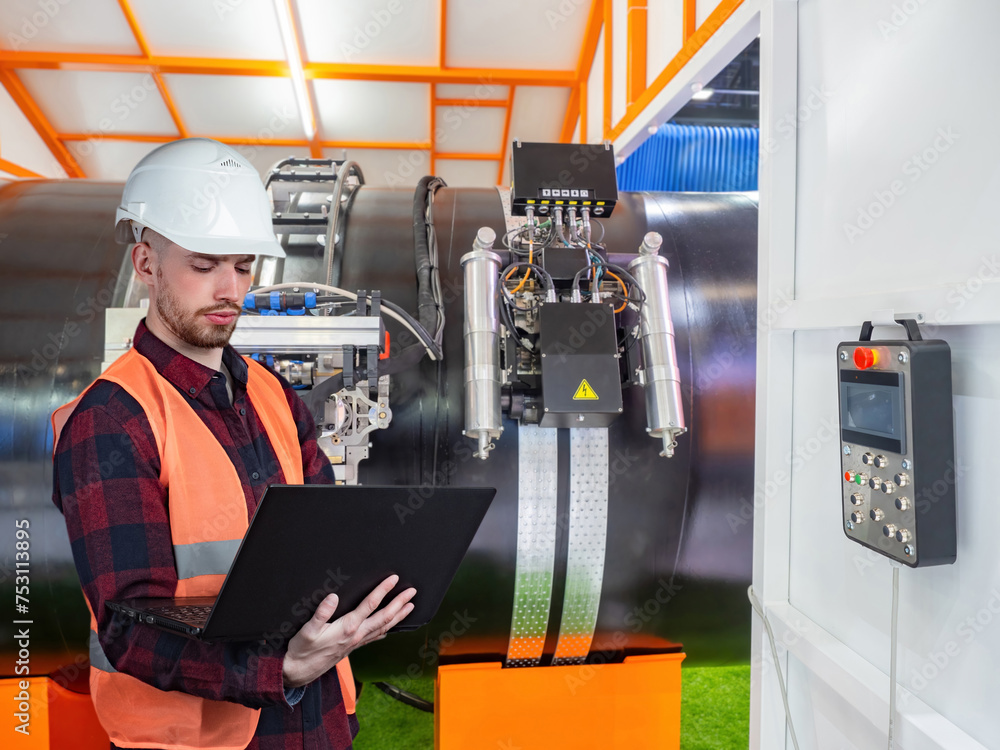 Man engineer. Production of large diameter pipes. Worker controls robot ...
