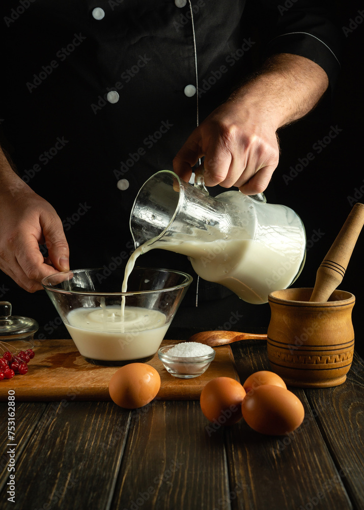 A professional chef prepares a milkshake with fruits in the kitchen ...
