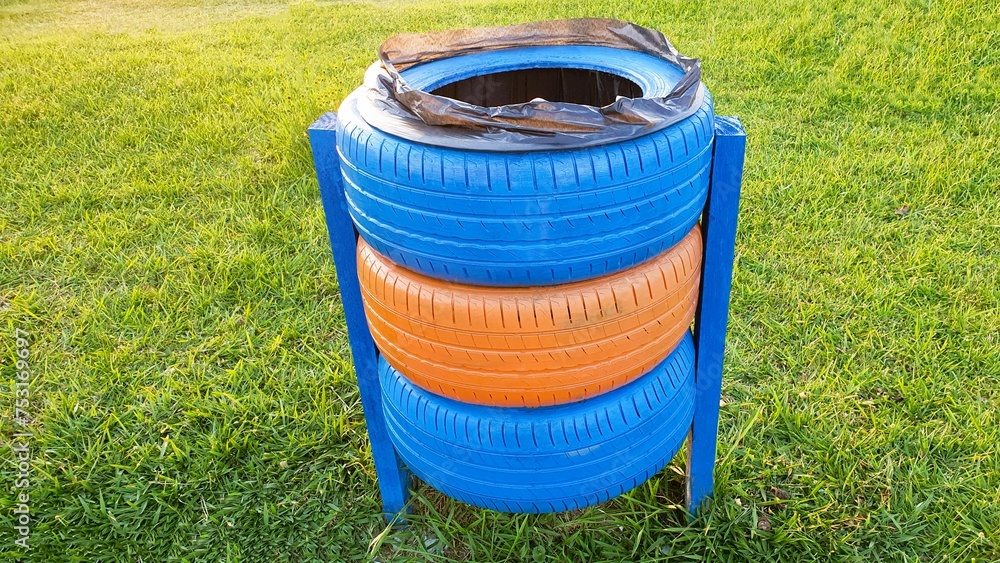 Trash bin made from old colored tires with a plastic bag for garbage ...