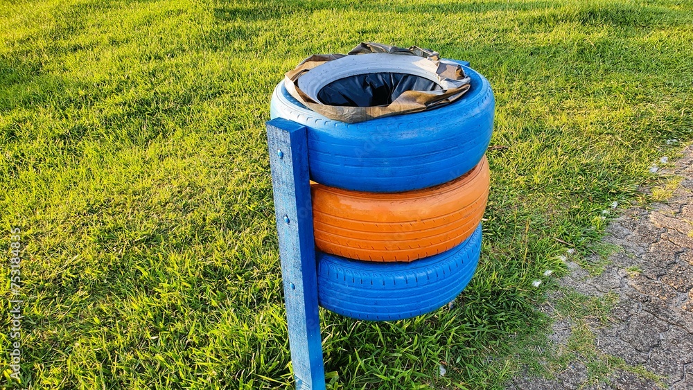 Trash bin made from old colored tires with a plastic bag for garbage ...