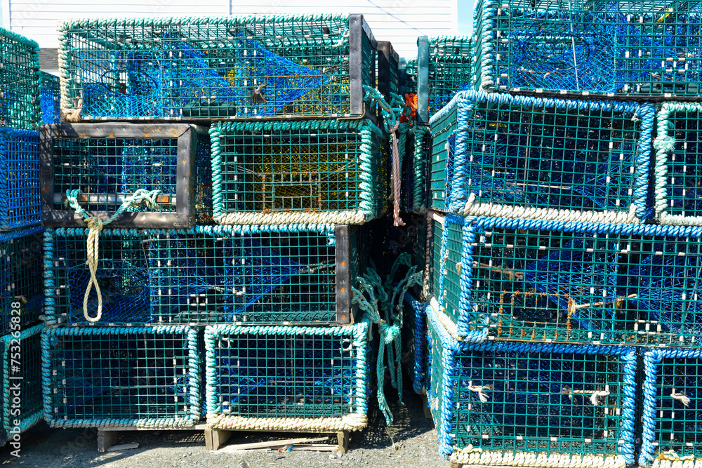 Multiple yellow lobster pots or traps stacked high along a wharf ...