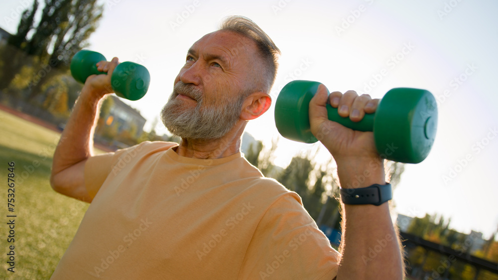 Aged Caucasian European man sportsman lifting dumbbell weightlifting ...