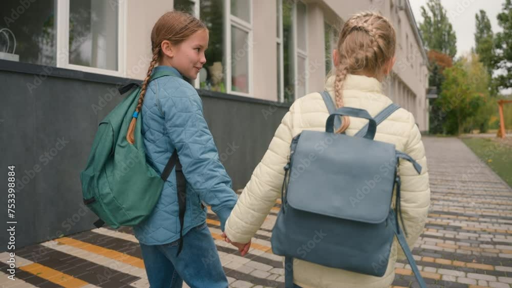 Back view two schoolgirls walking street city outside holding hands ...