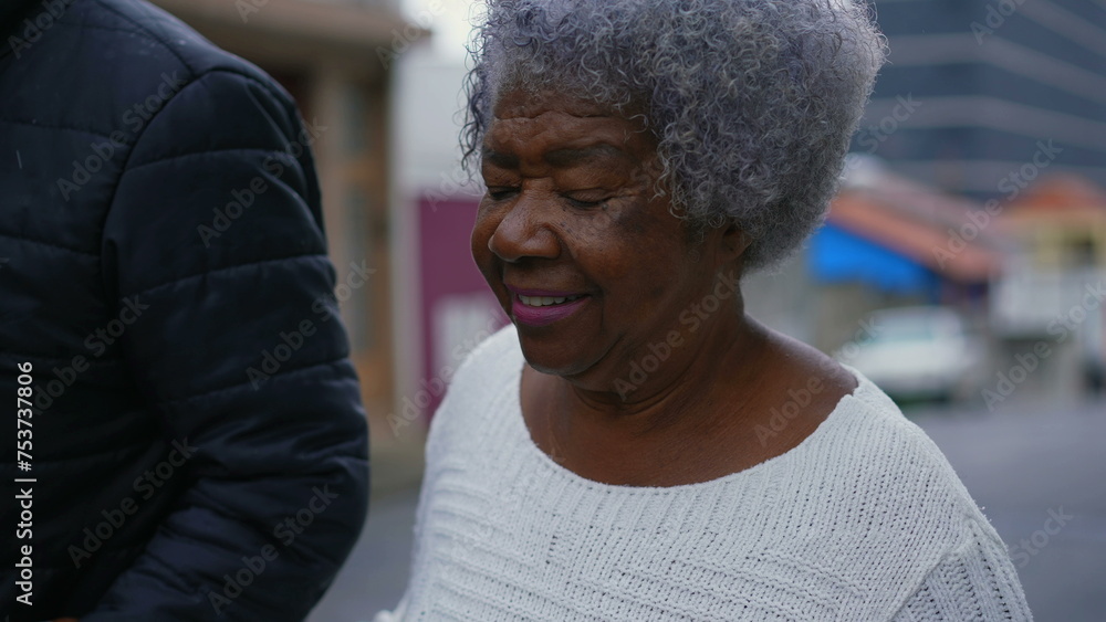 African American senior lady strolling in street with the help of her ...