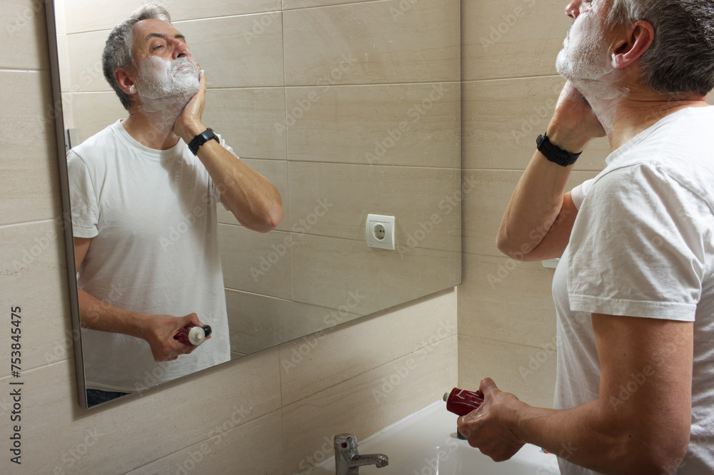 Man with gray hair and a defect on his hand shaving in front of the ...