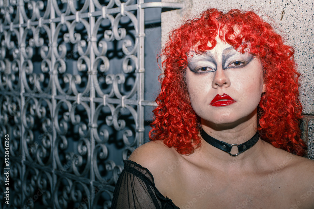 Gothic curly redhead poses in front of a gothic window grill Stock ...