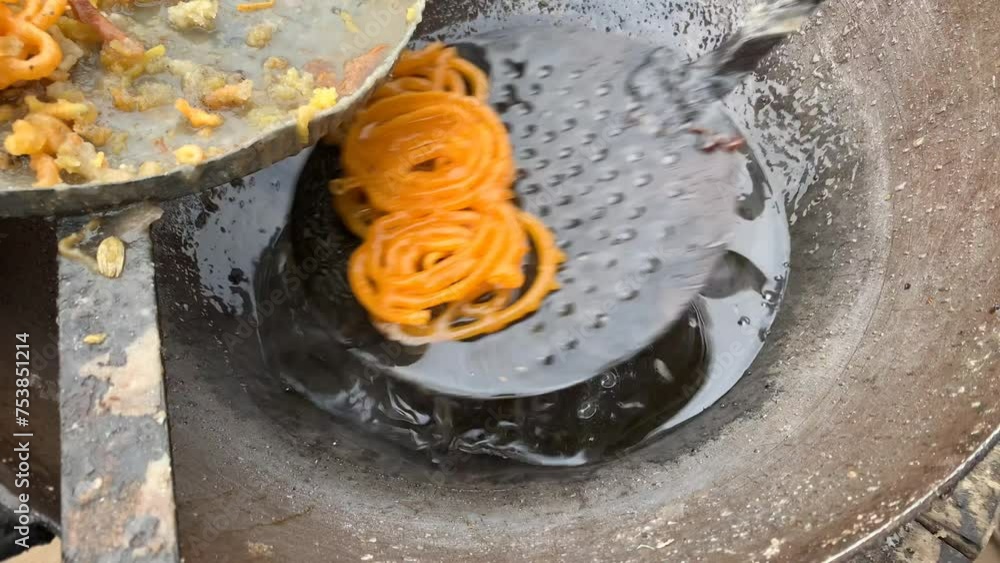 man making traditional sweet orange jalebi snacks on a street food ...