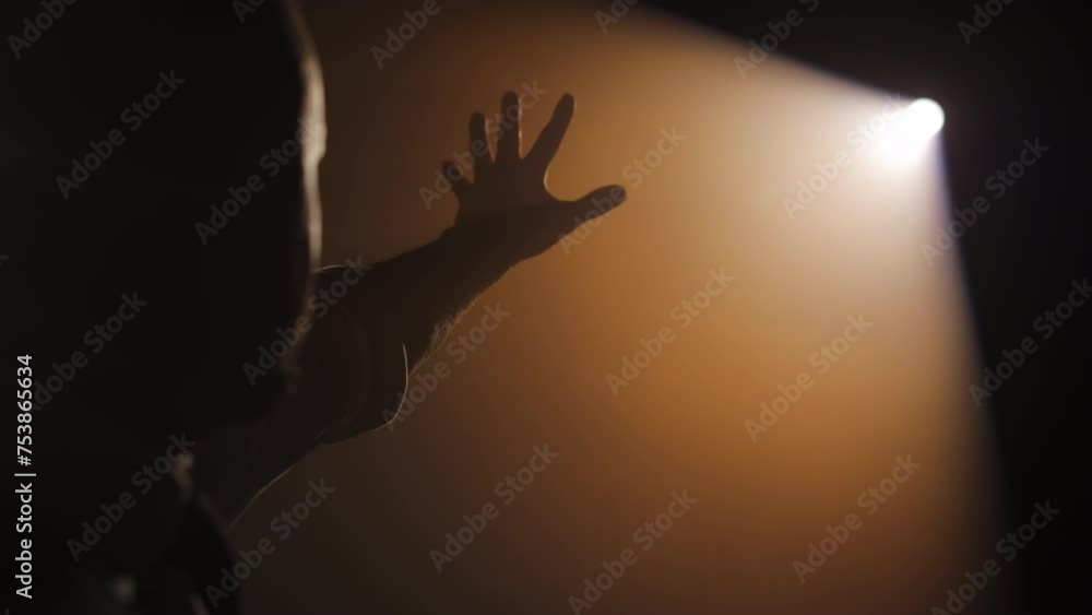 Back view of male silhouette standing against contrast spot light with ...