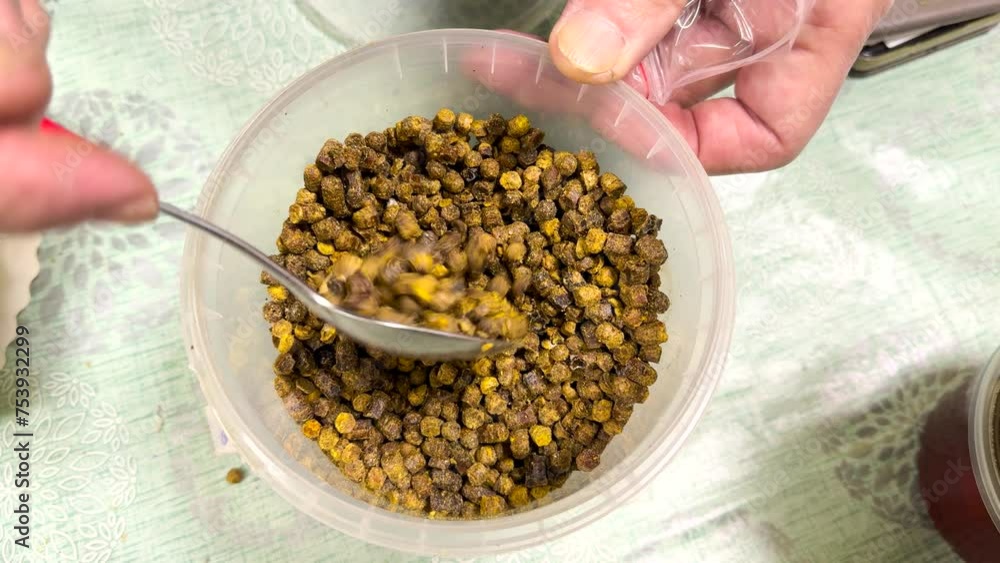 The seller's hand stirs bee perga, ambrosia, bee pollen in a plastic ...