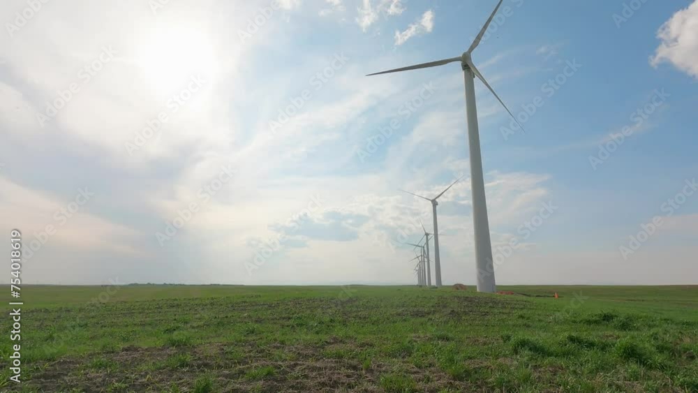 driving alone wind turbines line up on the green field with heavenly ...