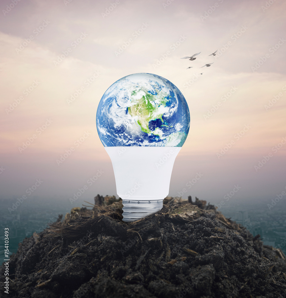 Earth globe inside led light bulb on soil over city tower and ...