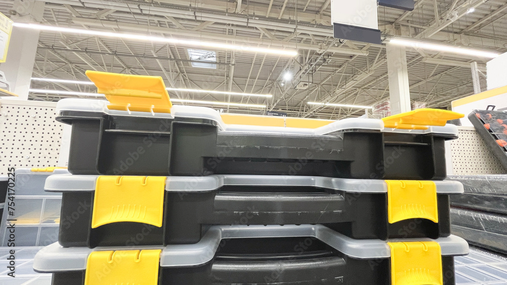A shelf of plastic containers with yellow handles. The containers are ...