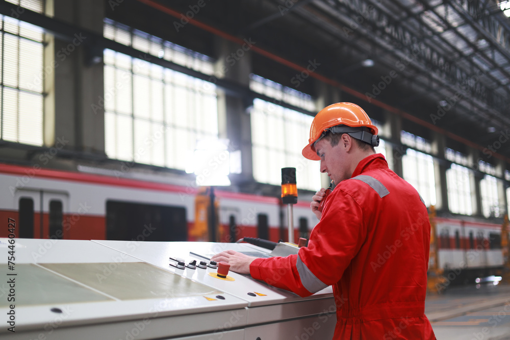 The male railway engineer wearing a red safety suit is working on the ...