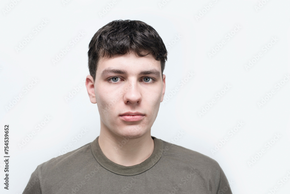 Young guy with a serious face on a light background, the guy has dark ...