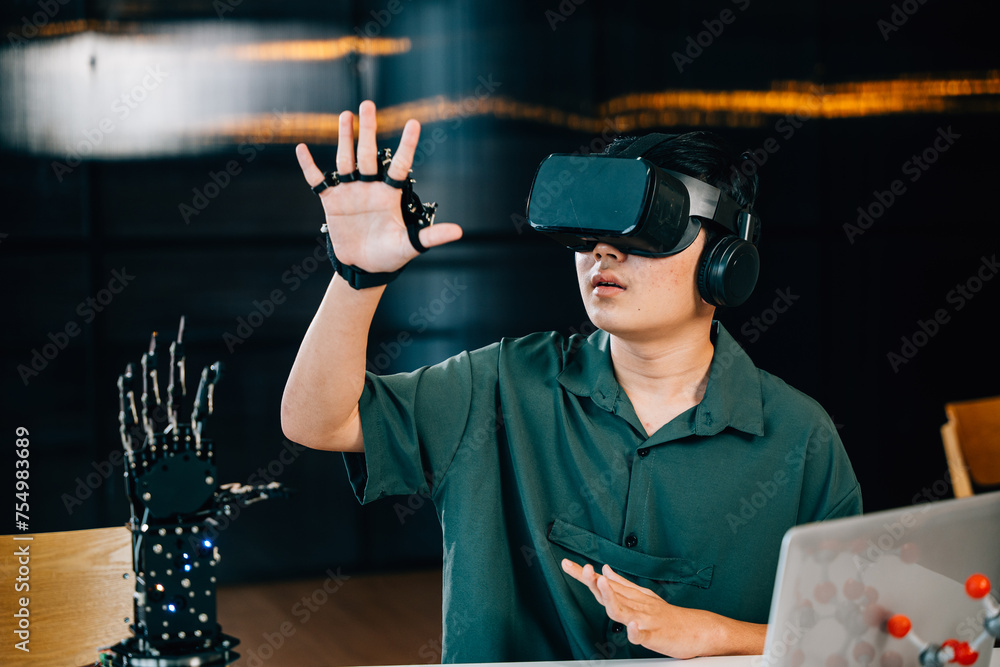Teenager in VR glasses controls a robot arm project in a classroom ...