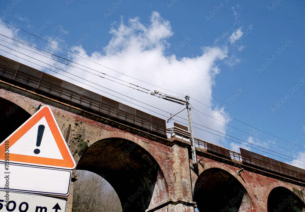 Red solid brick railway bridge, with warning road signs to the left of ...
